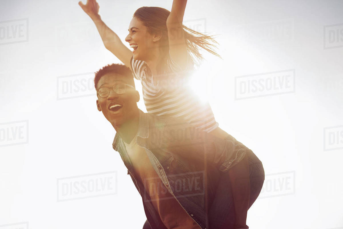 Happy young african man carrying his friend on his back on a bright ...