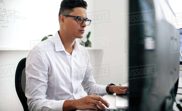 Software developer sitting in front of computer and working in office ...