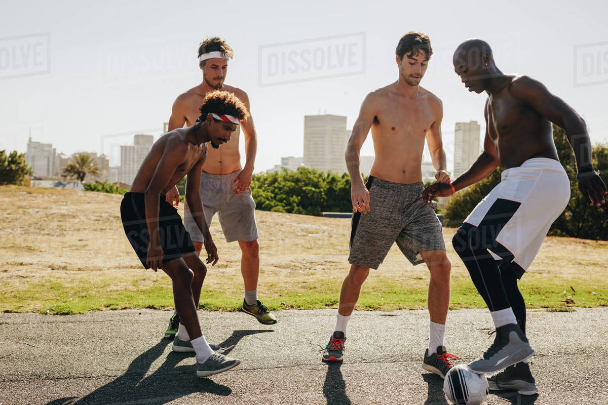 Four men playing football in play area. Men practicing football on a ...