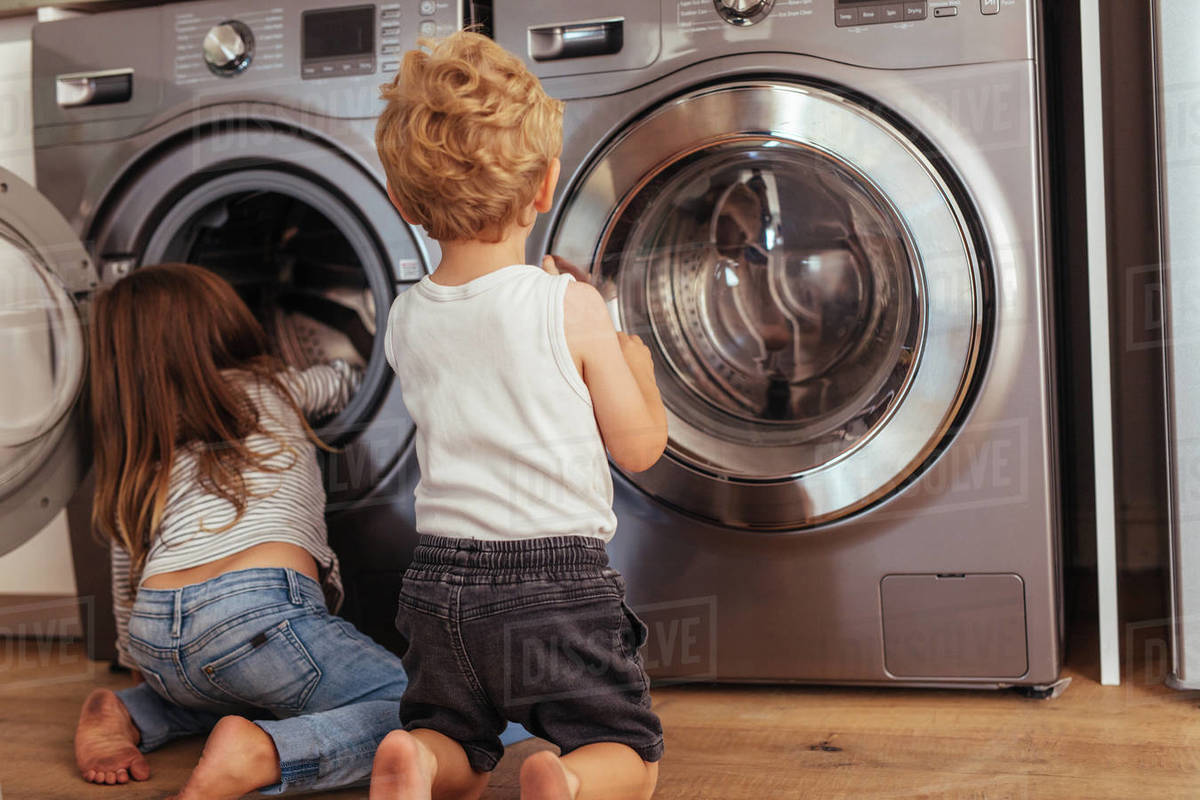 Rear view of children sitting near washing machine and playing. Kids ...