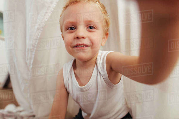 Adorable little boy looking at camera and smiling. Small kid at home ...
