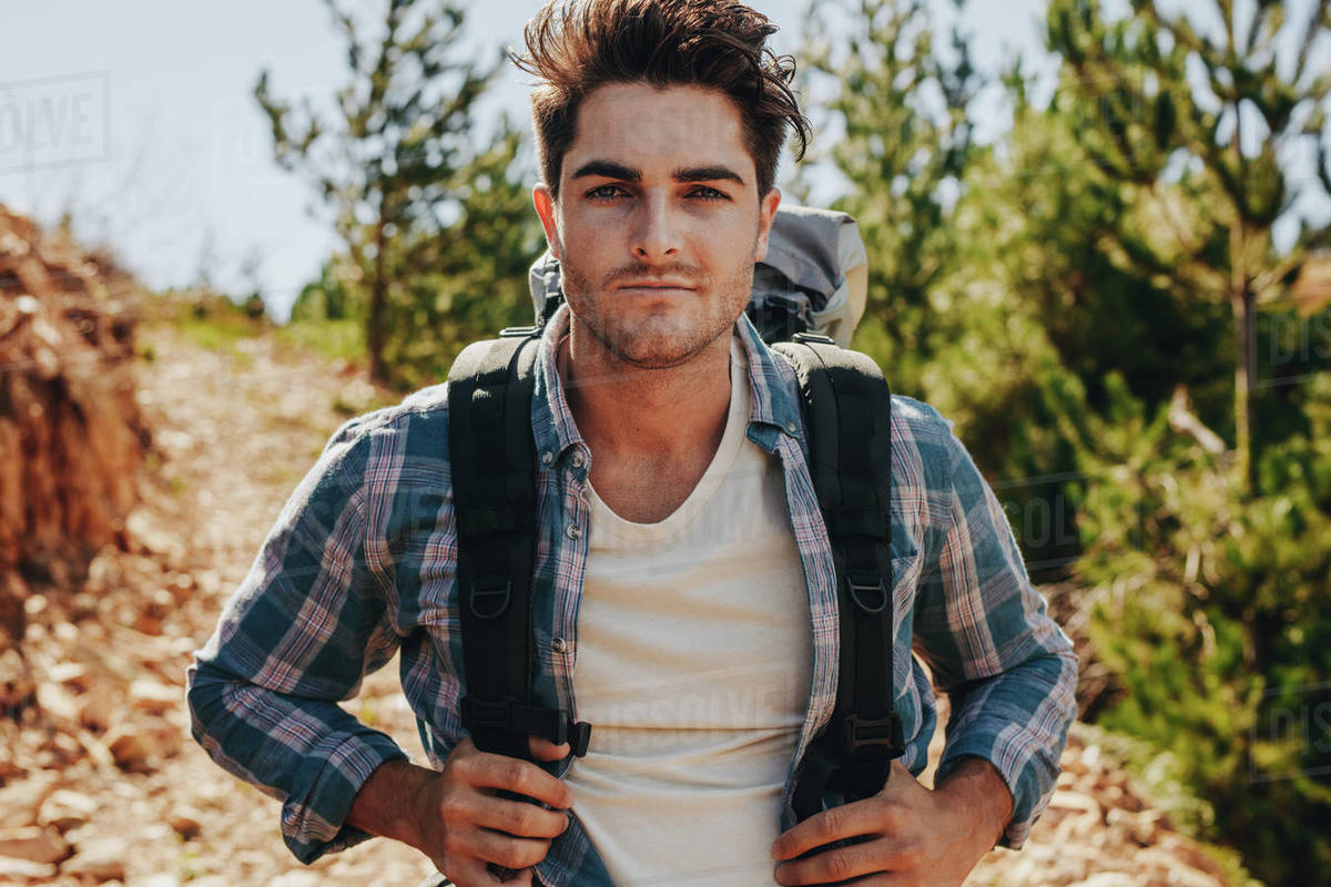 Handsome young guy with backpack walking down the mountain trail. Male ...