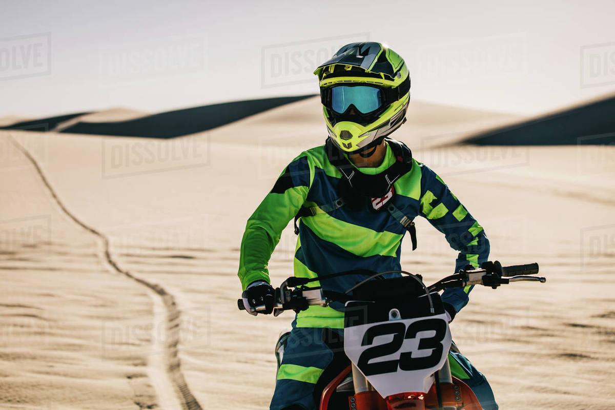 Portrait of male motocross rider sitting on his bike in full protective ...