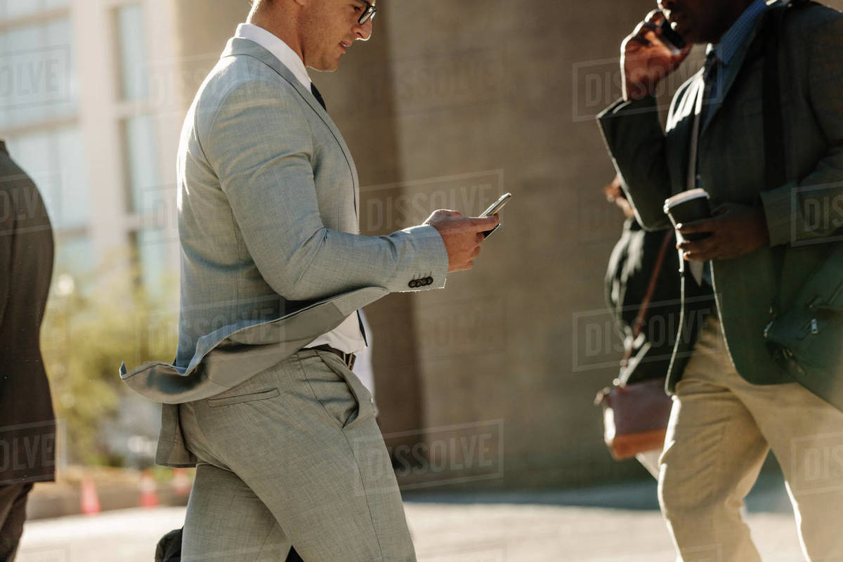 Men in formal clothes using mobile phone while commuting to office ...