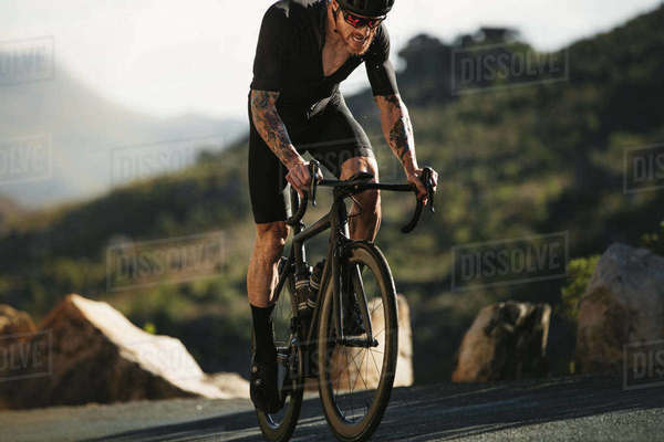 Professional male cyclist riding his bike on a mountain road. Sportsman ...