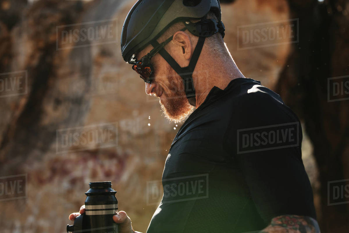 Cyclist making a short break, drinking water to stay hydrated during ...