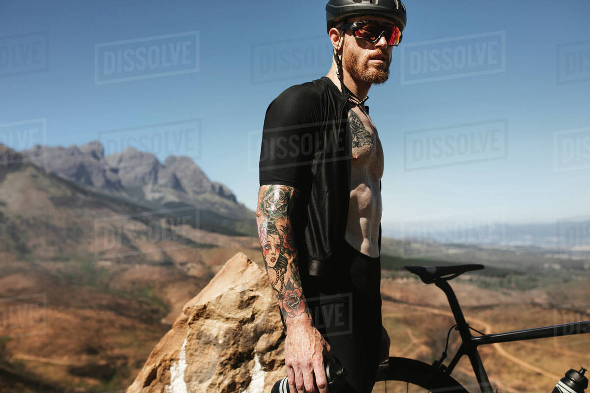 Portrait of exhausted male cyclist taking break during intense cycling ...