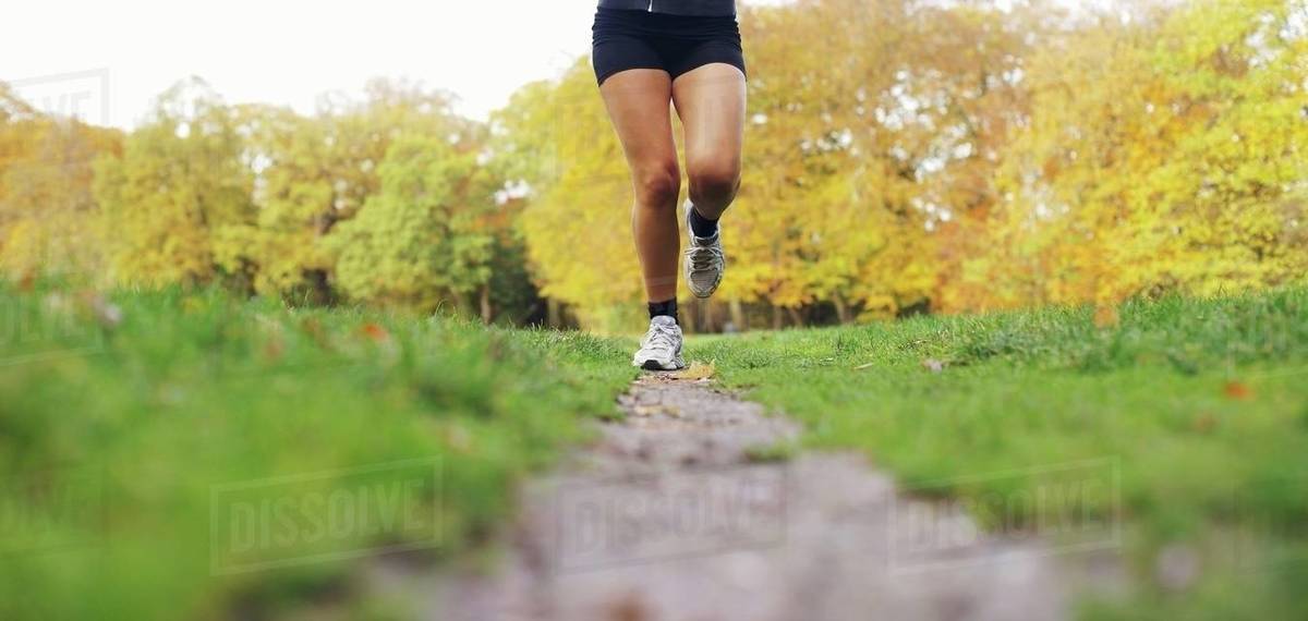 Low section image of young woman's legs running in park. Female athlete ...