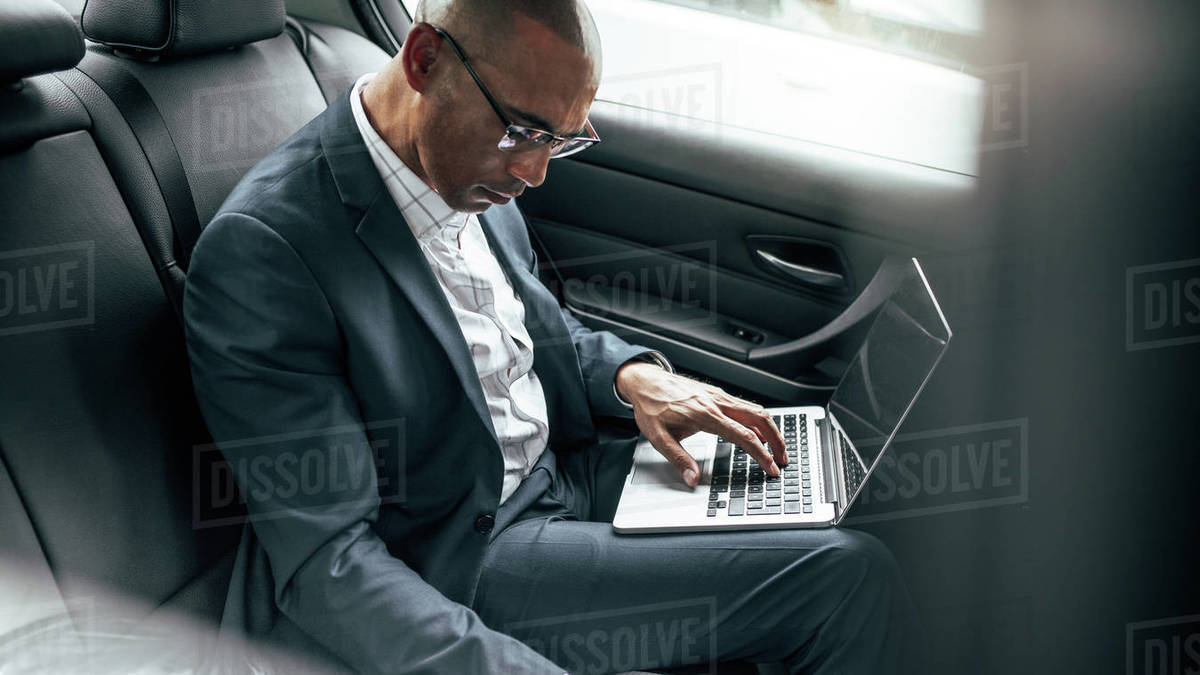 Businessman working on laptop computer while commuting to office in his ...