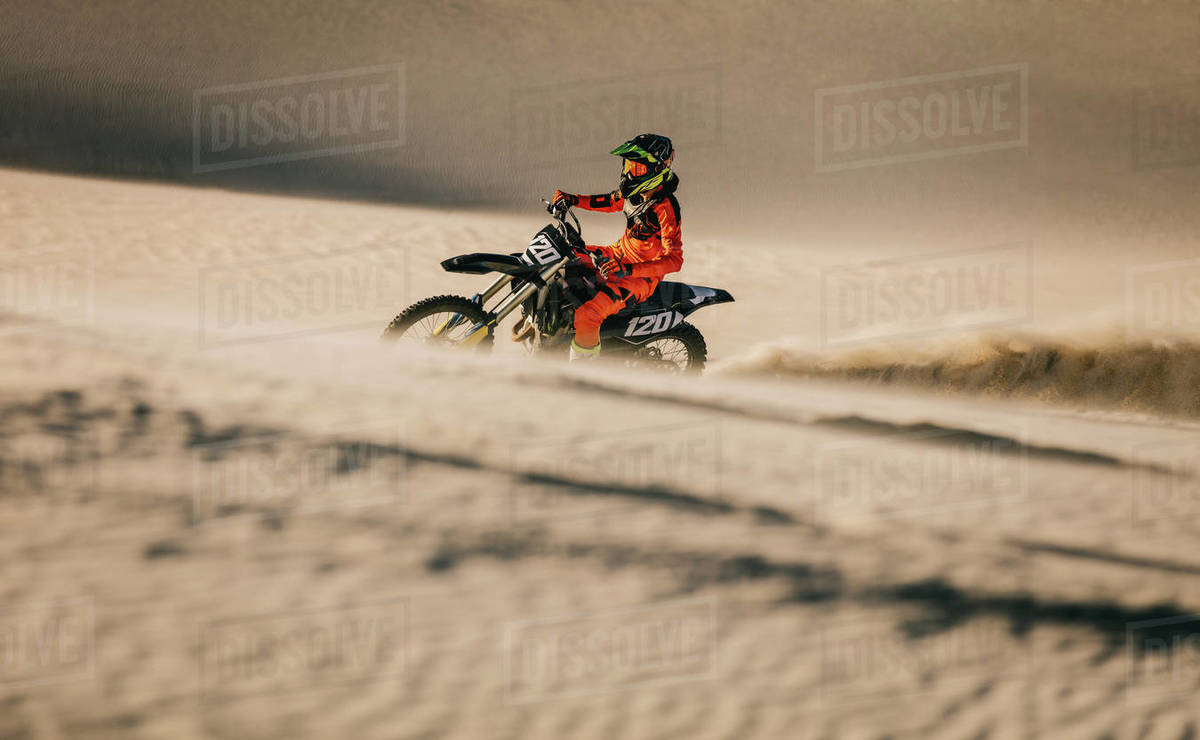 Motocross rider riding his bike on a sand dune. Motorcycle rider in ...