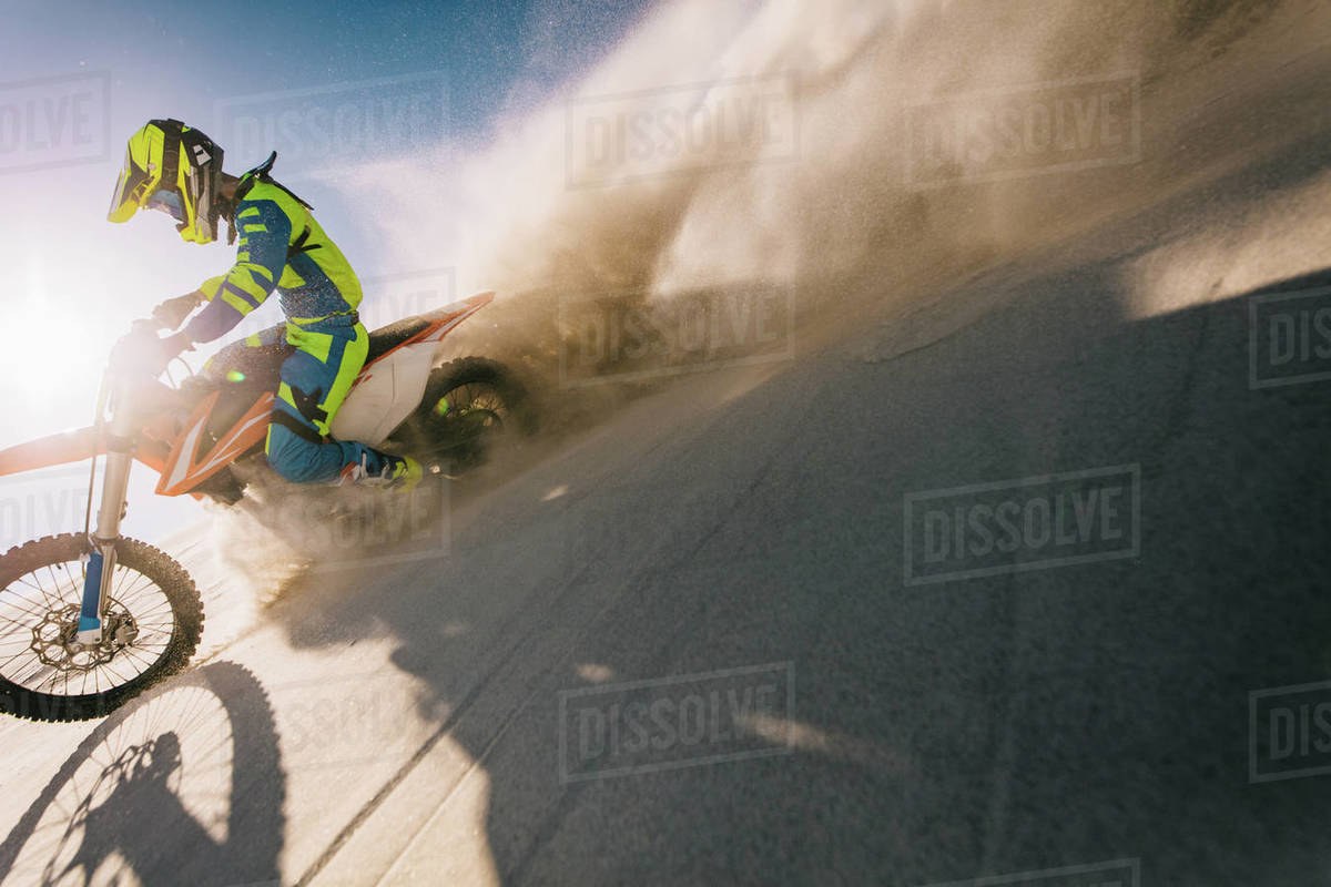 Motocross biker riding his racing bike on a sand dune. Professional ...