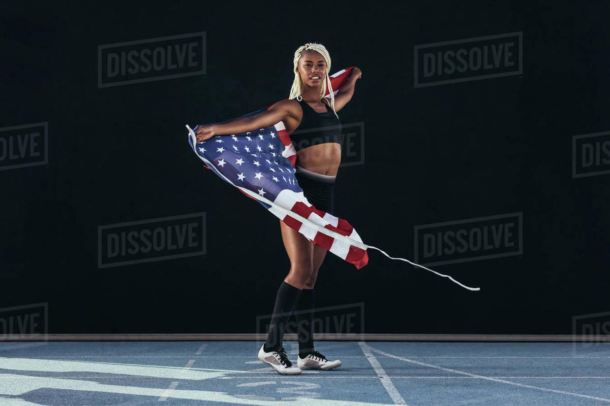 Female athlete walking on running track celebrating victory holding ...