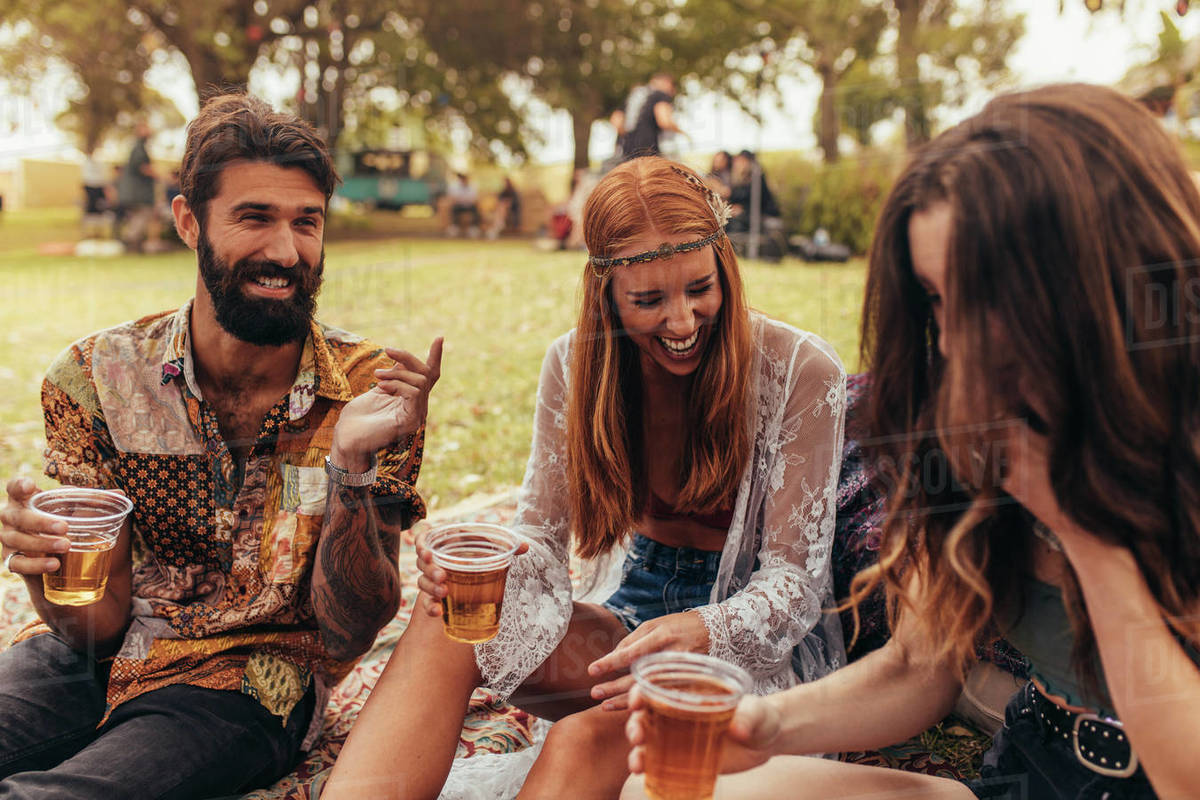Happy friends partying at park with drinks. Group of friends having a ...