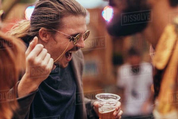 Excited young man with a glass of beer dancing at music festival. Male ...