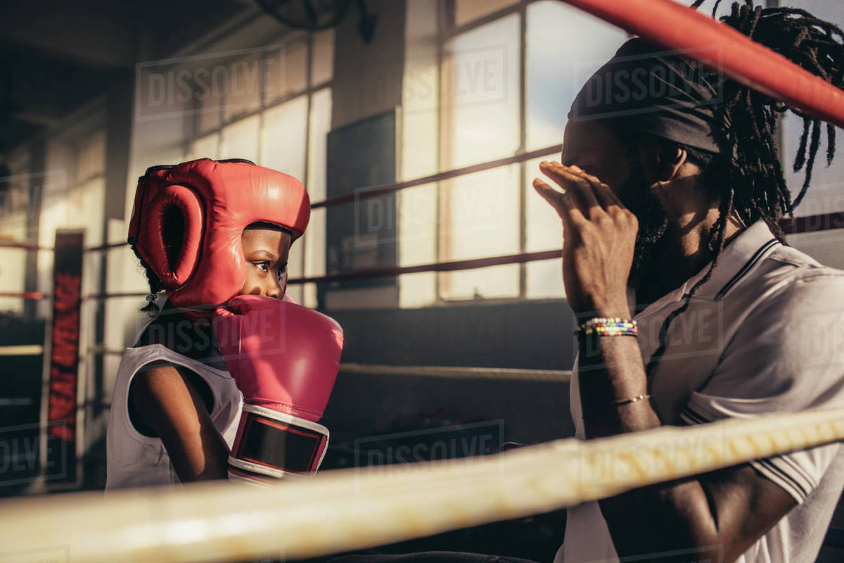 Boxing coach giving instructions to a kid at a boxing gym. Kid wearing ...