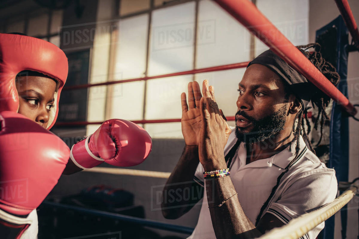 Close up of a boxing kid training with his coach inside a boxing ring ...