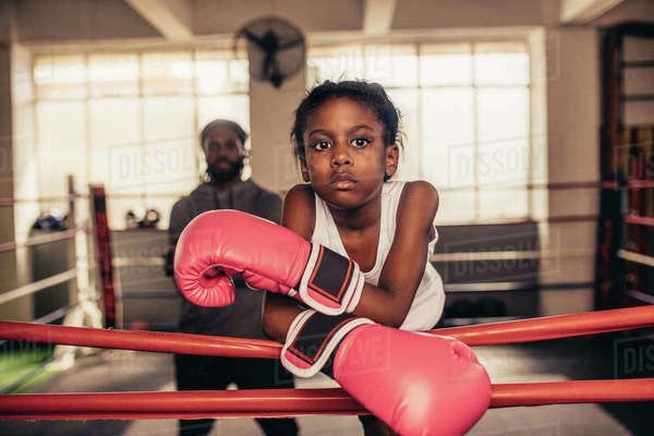 Confident looking boxing kid standing inside a boxing ring with her ...