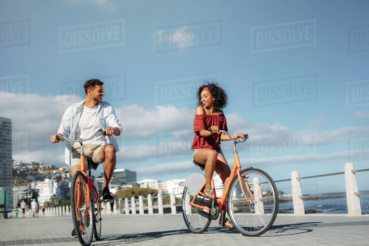 Happy man and woman riding bicycles in the street. Smiling couple ...