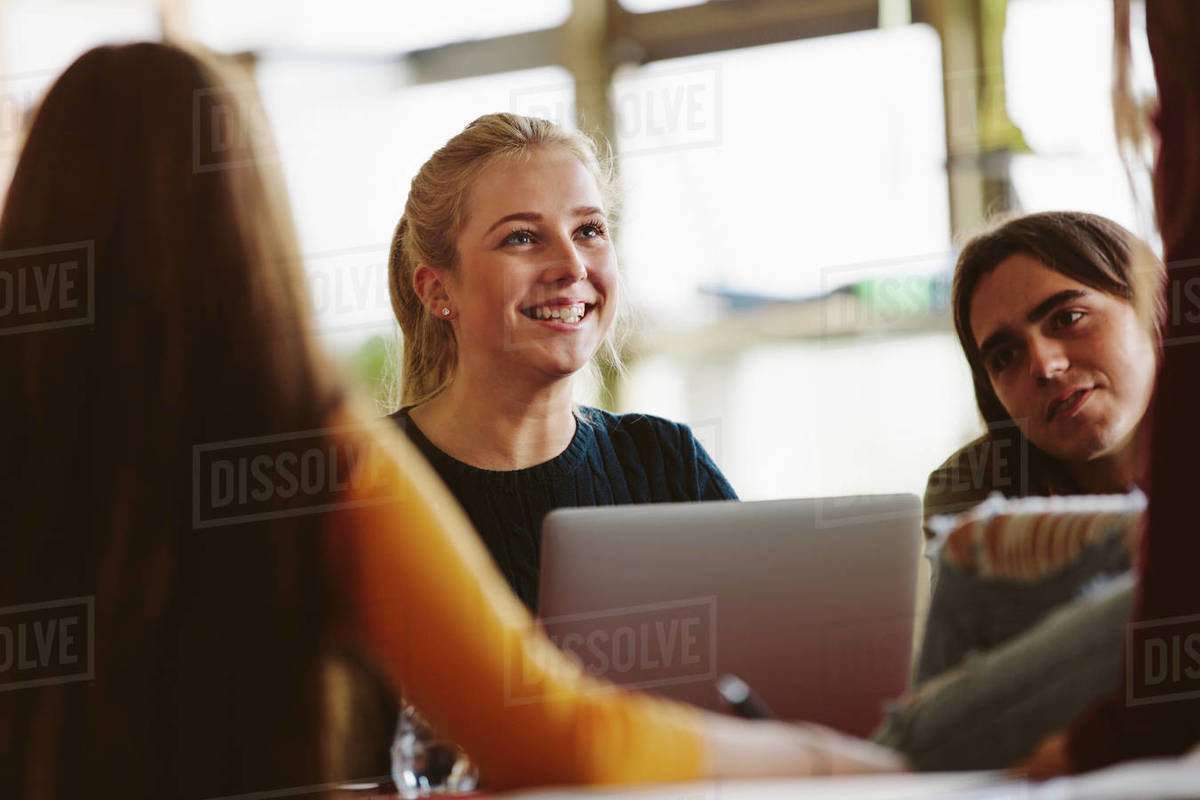Beautiful young female student talking with classmates in classroom ...