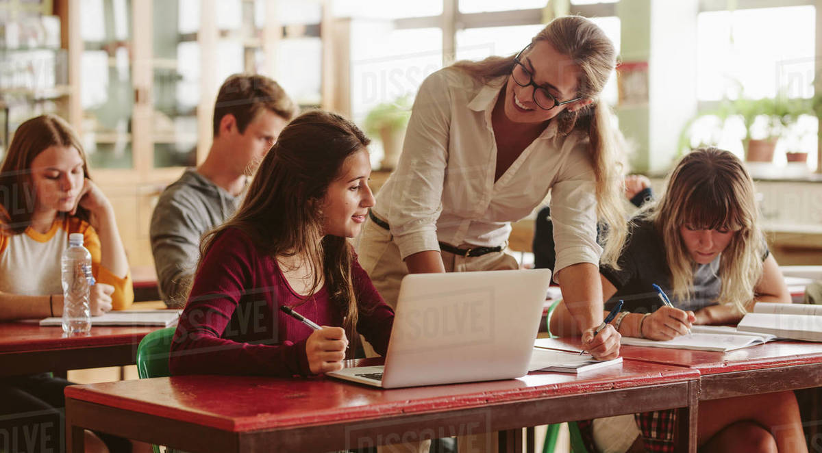 Smiling female lecturer helping student during her class. Student in a ...