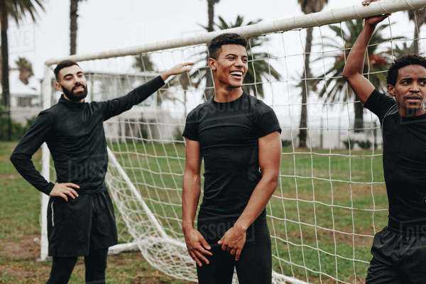 Three footballers standing at the goalpost taking a break during a ...