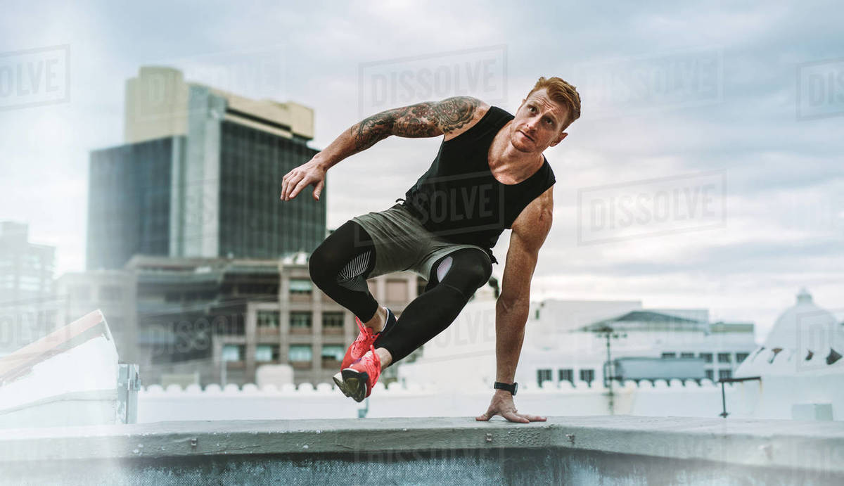 Man doing fitness training on rooftop. Muscular man jumping on to the ...
