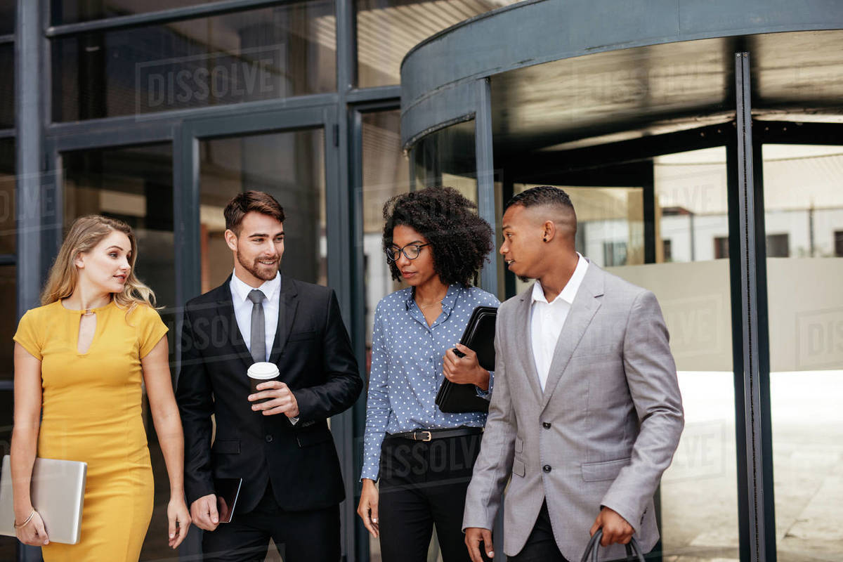 Group of corporate professionals walking out of office together and ...