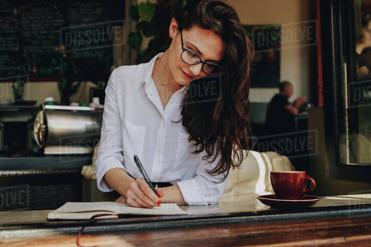 Beautiful woman sitting near a window at cafe and making some important ...