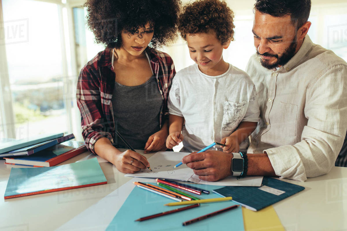 Couple writing in a book together with their kid sitting in the centre ...