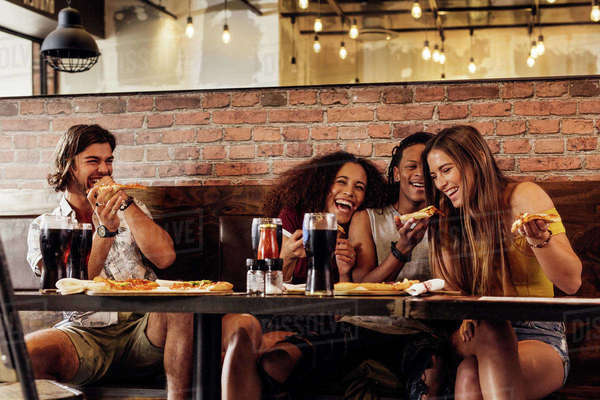 Group of friends having pizza at cafe. Cheerful young people eating ...