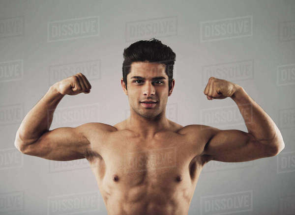 Portrait of macho and muscular man pulling his bicep to show off ...