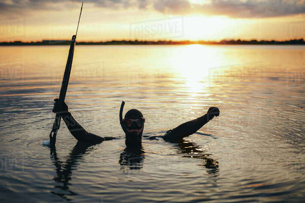 Portrait of spearfishing diver submerged in sea water with his hands ...