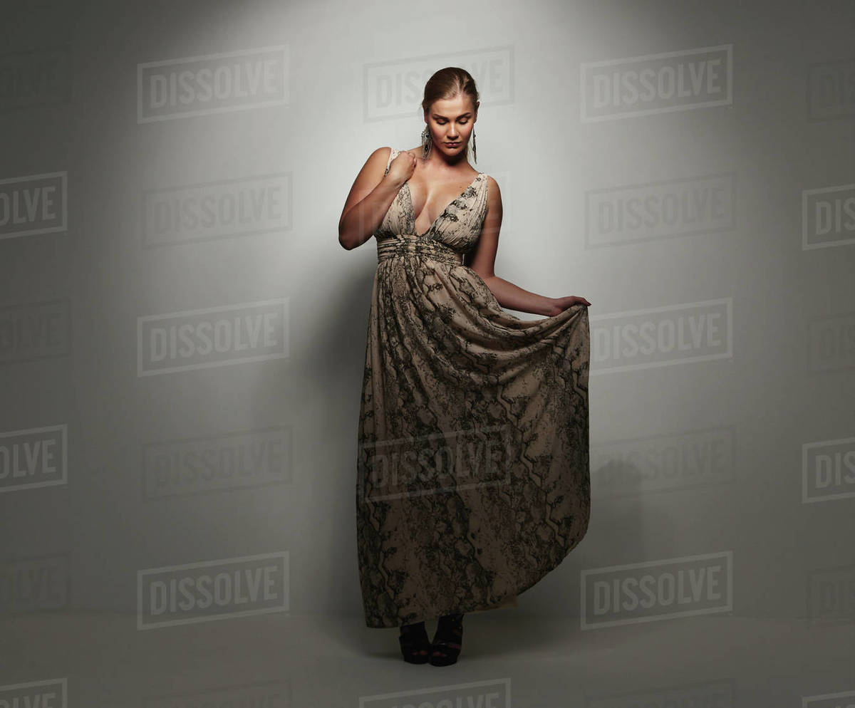 Pretty young lady in a evening dress standing on grey background. Plus ...
