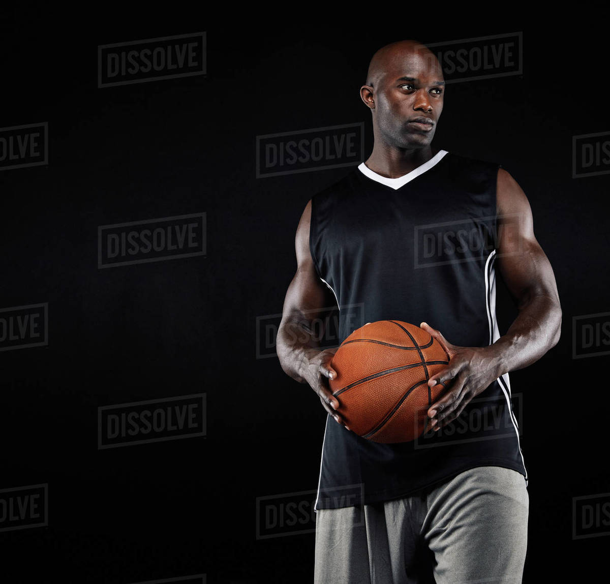 Studio shot of black basketball player with ball looking away against ...
