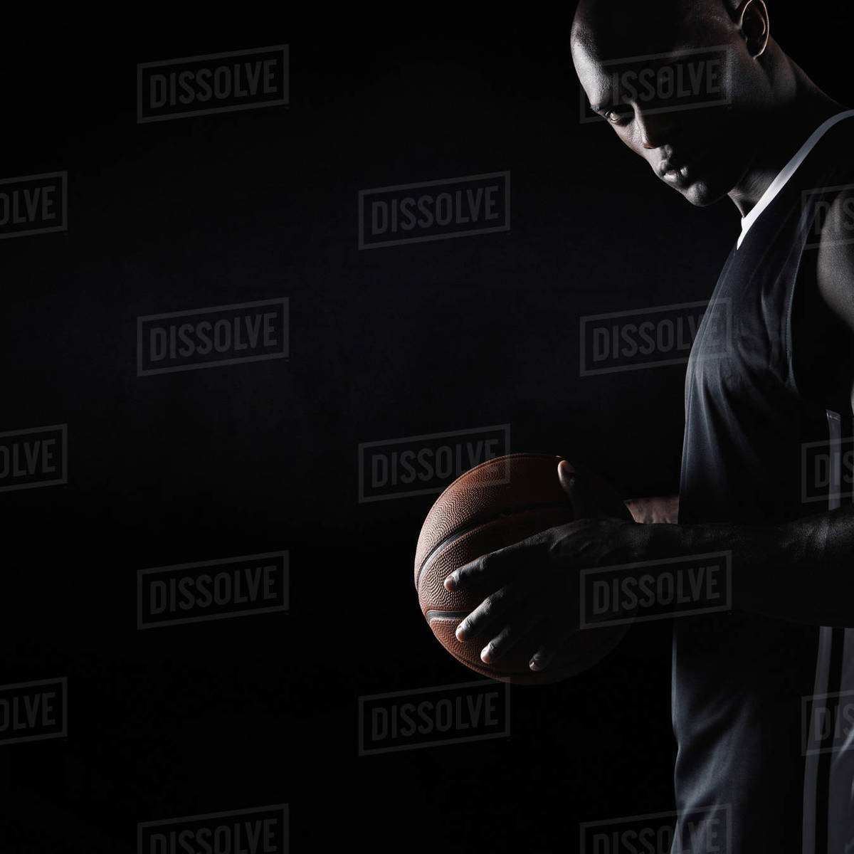Studio shot of strong young man holding basketball looking at camera ...