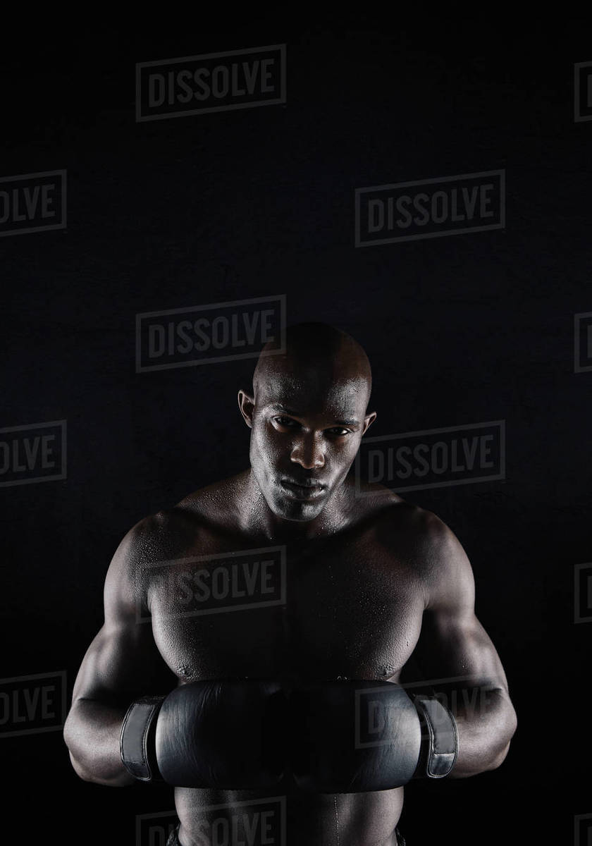 Portrait of professional male boxer against black background. Strong ...