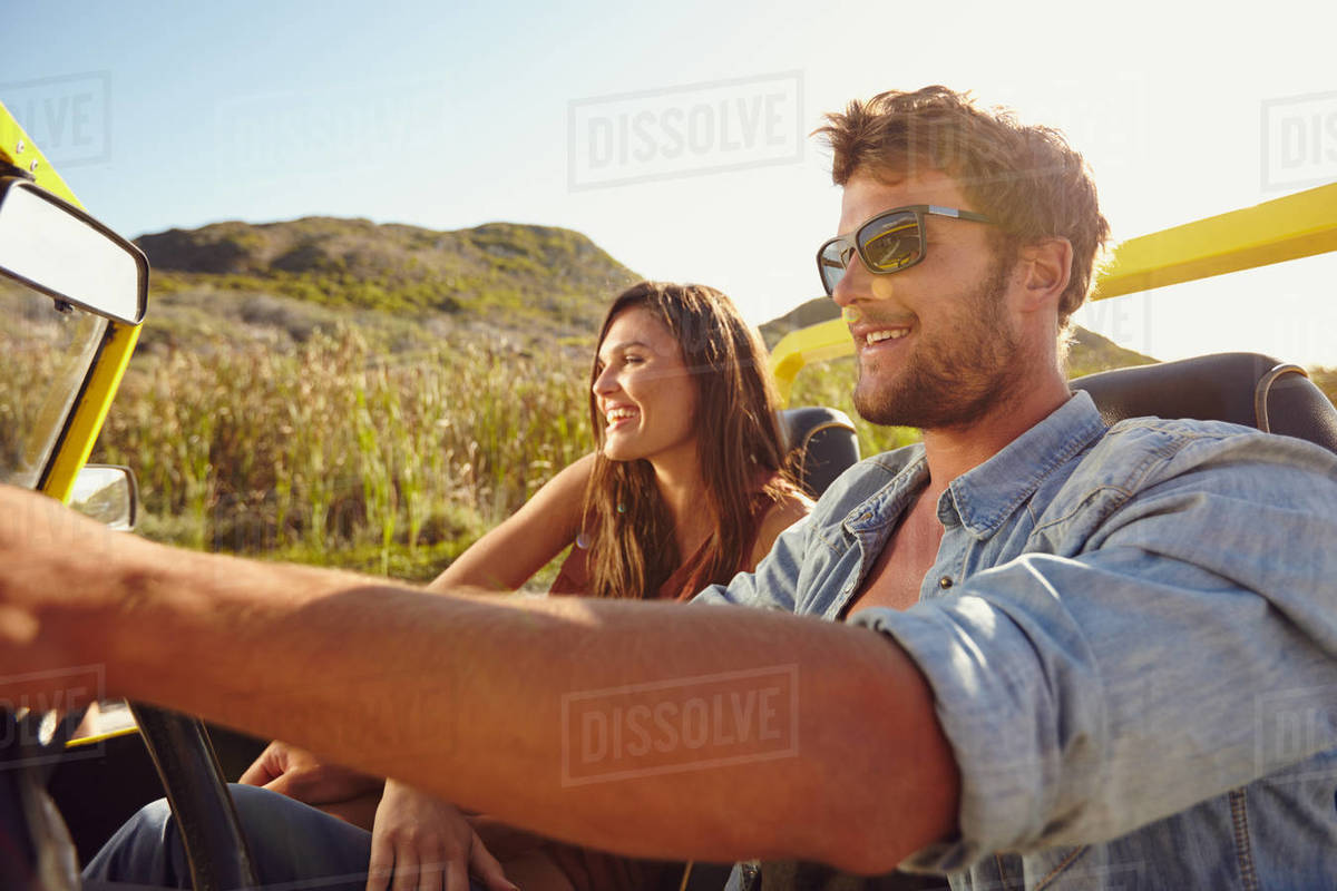 Young friends out for a drive together in a open topped car. Couple on ...