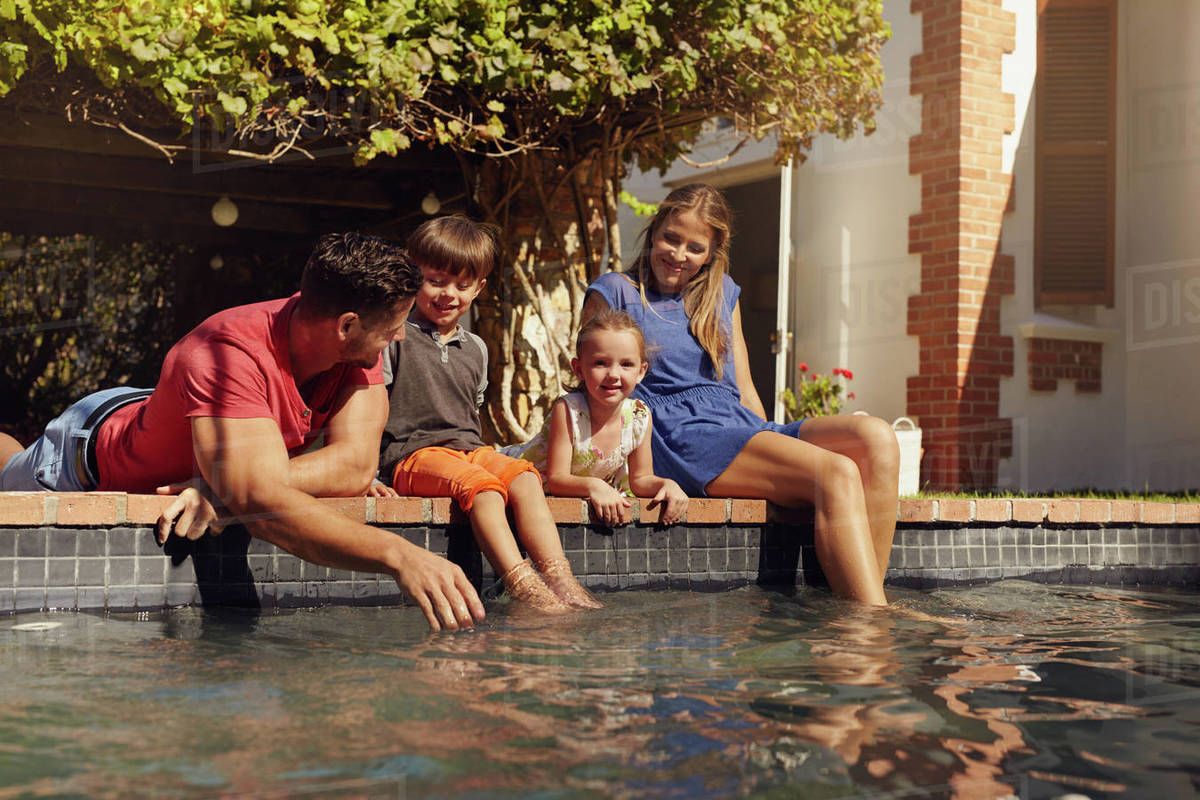 Portrait of young family with two children relaxing by their swimming ...