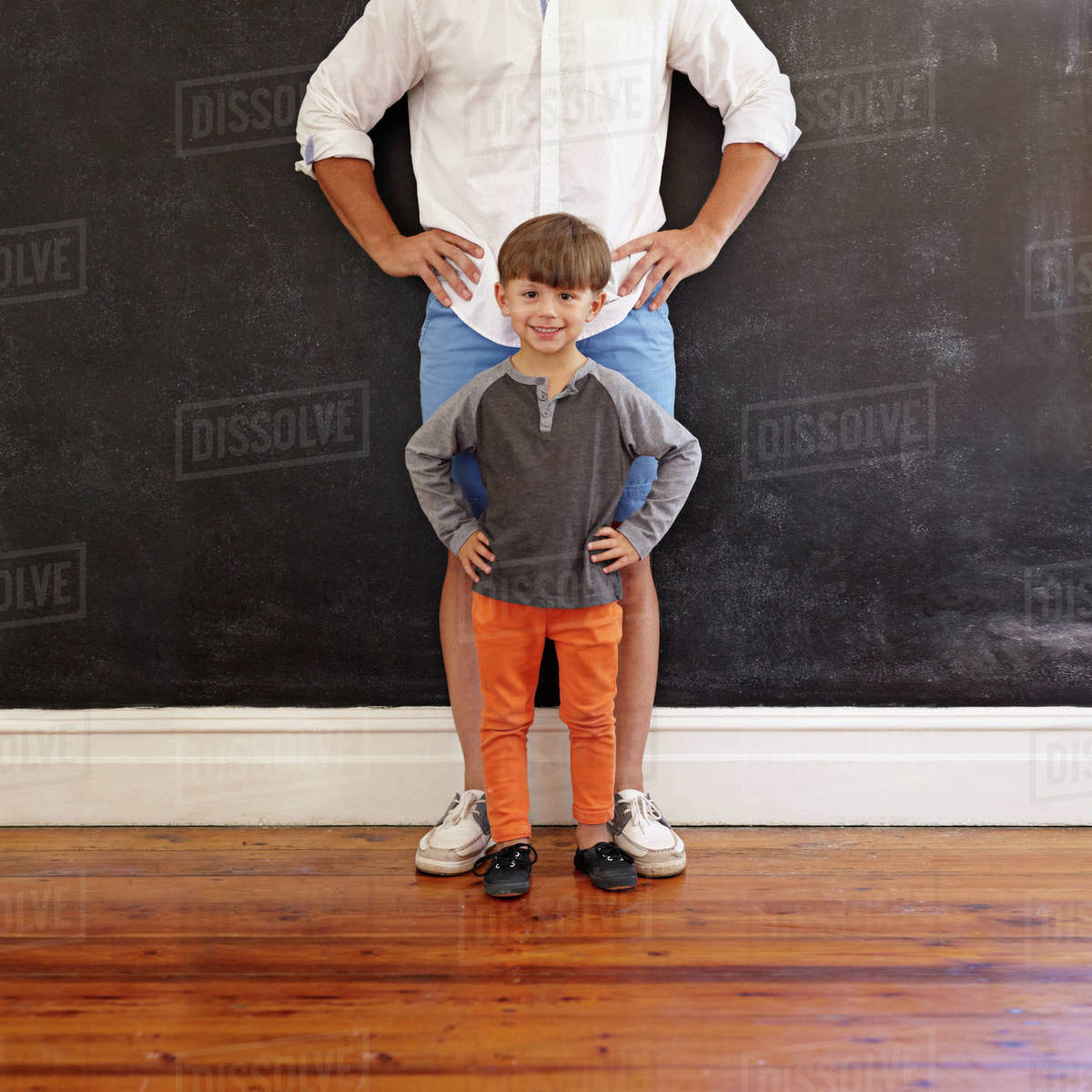 Indoor shot of little boy and his father standing with their hands on ...