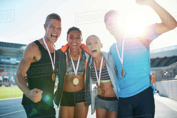 Portrait of ecstatic young runners with medals celebrating success in ...