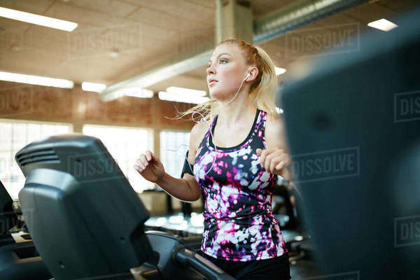 Shot of a woman running on the treadmill at gym. Young focused female ...
