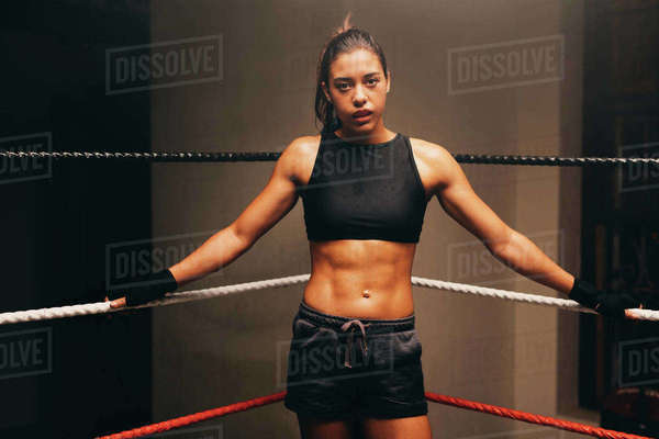 Fit young woman boxer with toned abdominal muscles standing in the ring ...