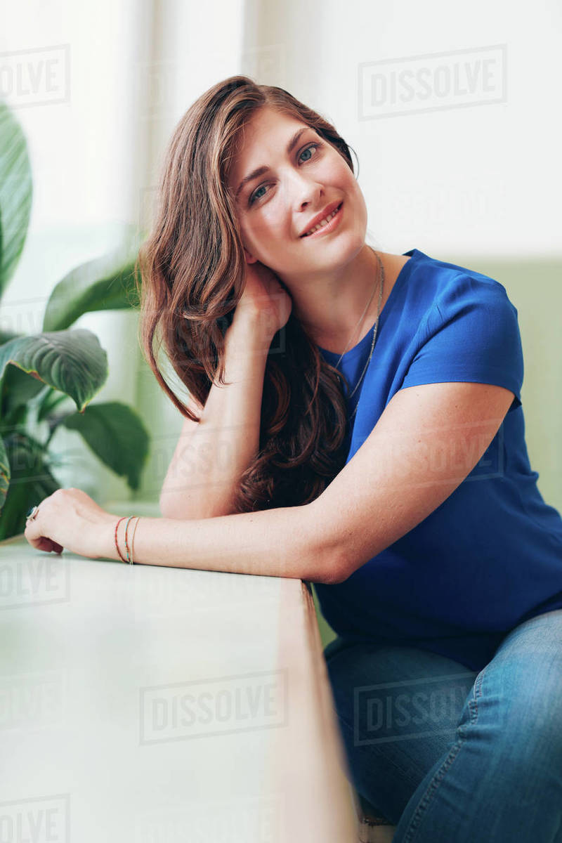Portrait of attractive young woman sitting at a table and looking at ...