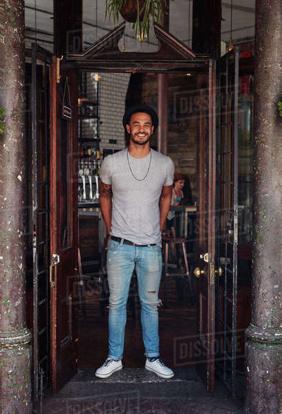 Full length portrait of stylish young man standing at the front door of ...