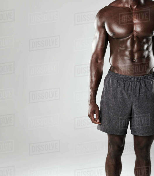 Cropped shot of young african muscular man body against grey background ...