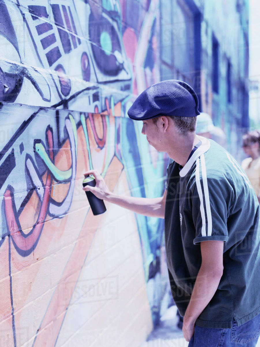 Teenage boy spray painting a wall - Royalty-free Stock Photo | Dissolve