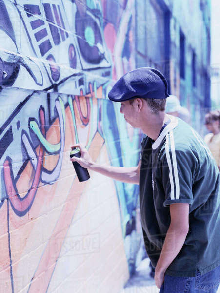 Teenage boy spray painting a wall - Royalty-free Stock Photo | Dissolve