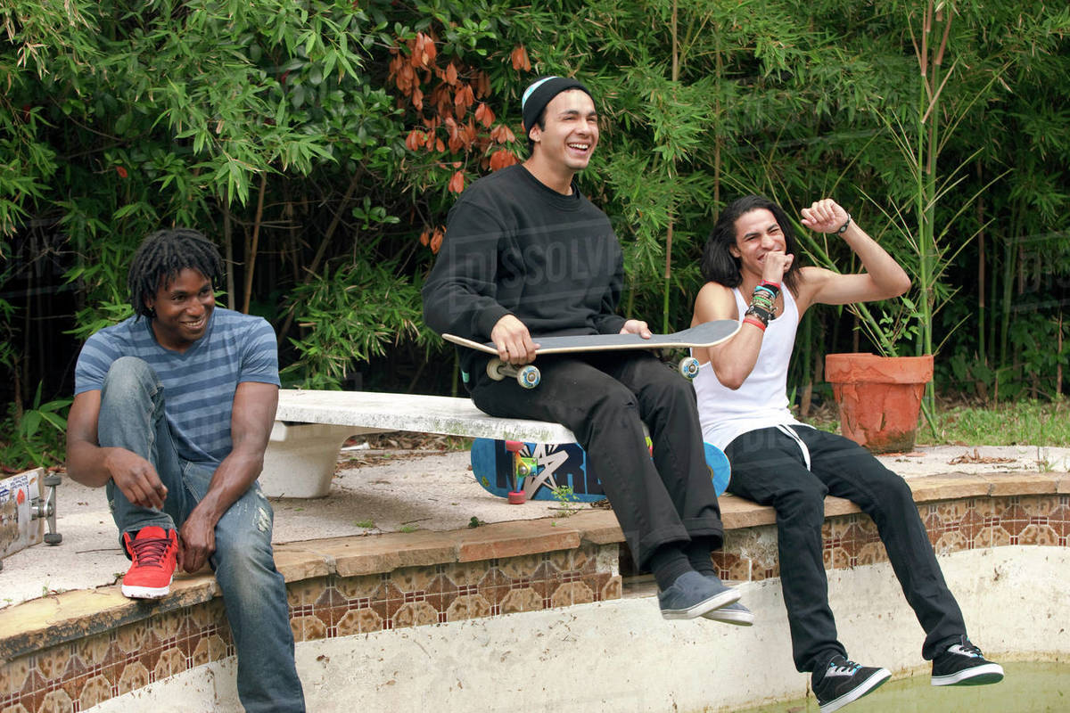 Friends hanging out at edge of disused swimming pool - Royalty-free ...