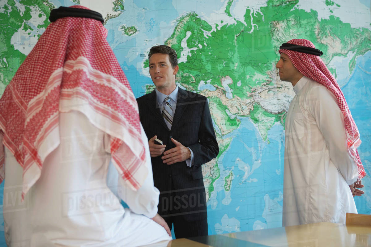Middle Eastern businessman talking to men in traditional clothing ...