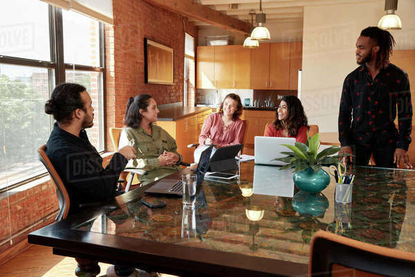 Group of co-workers sitting at large conference table with their ...